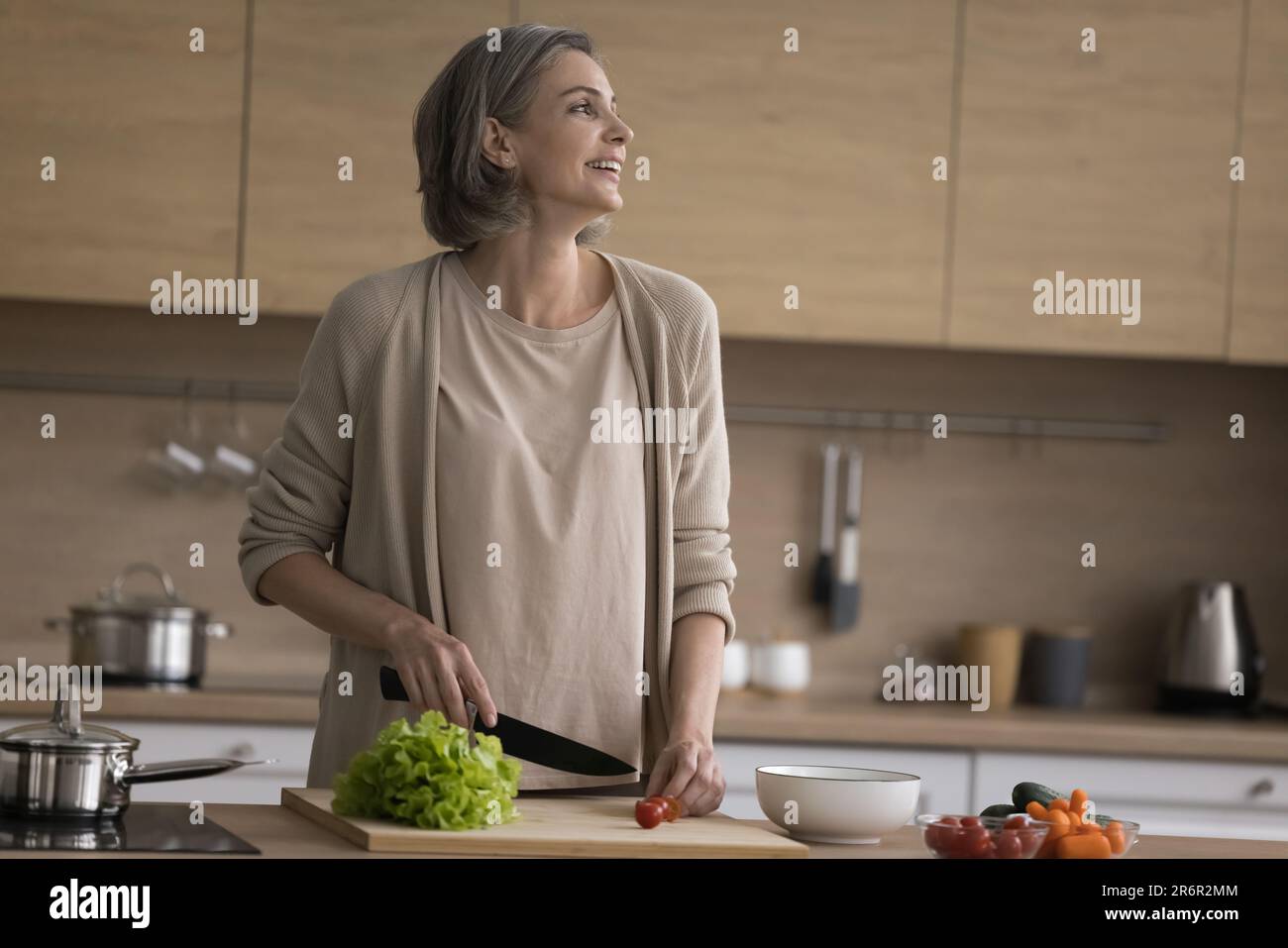 Happy middle aged woman enjoying cooking activity in home kitchen Stock ...