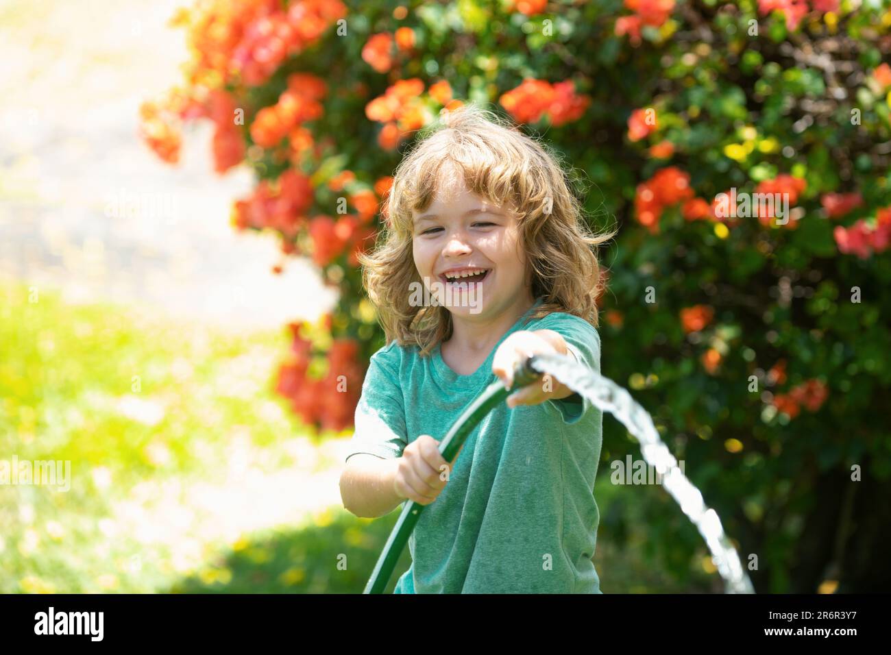 Adorable little boy is watering the plant outside the house, concept of ...