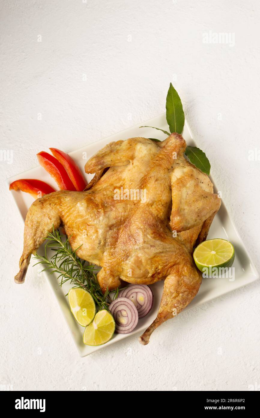 Baked tobacco chicken with spices and vegetables on a plate on a white ...