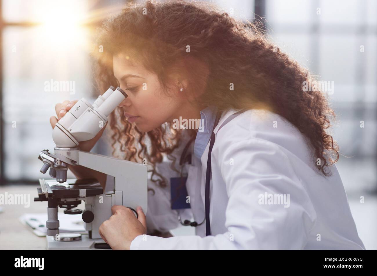 Attractive female scientist looking through a microscope Stock Photo ...