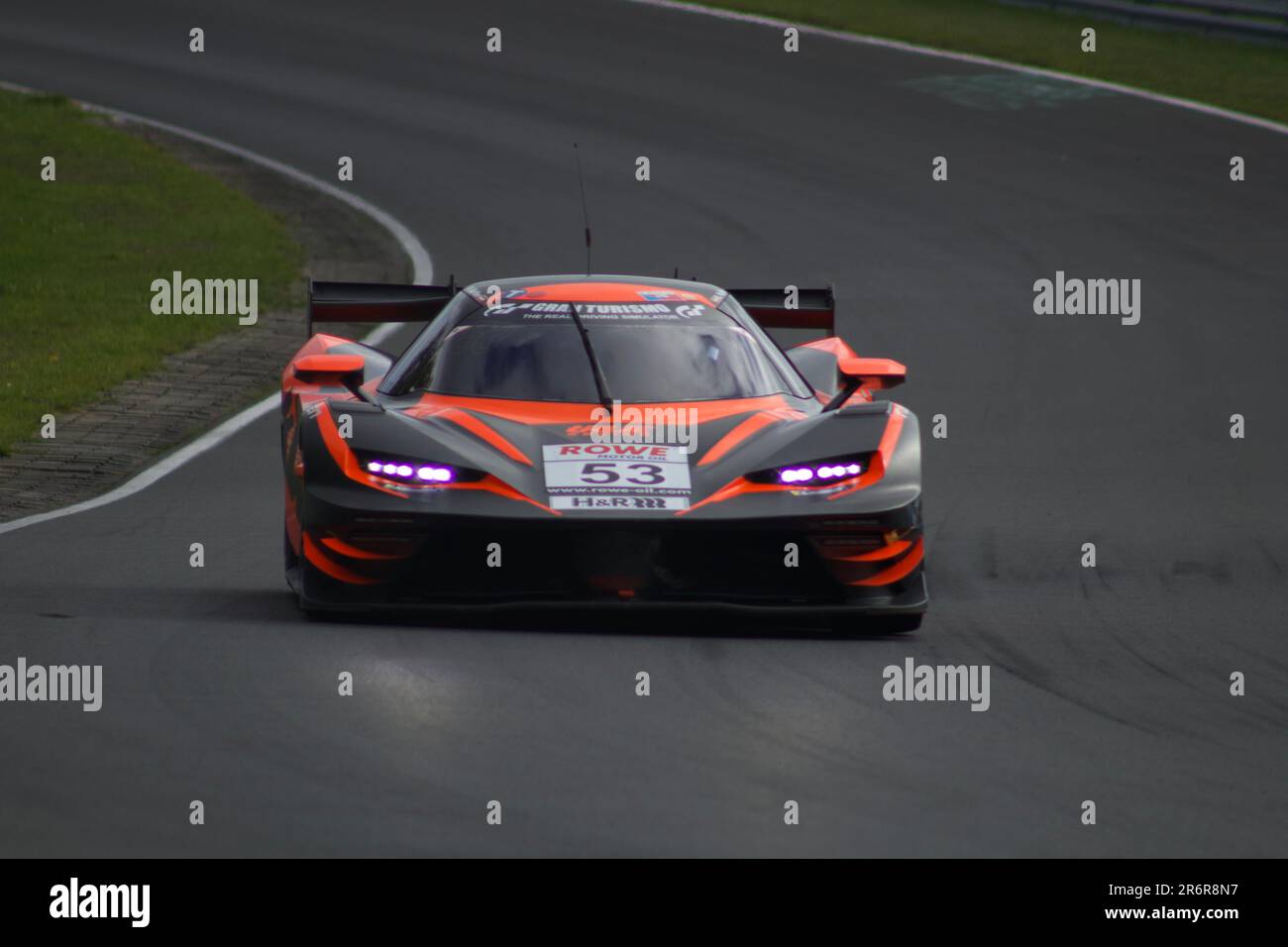 An orange race car driving on a track, perfect for any motorsport or ...