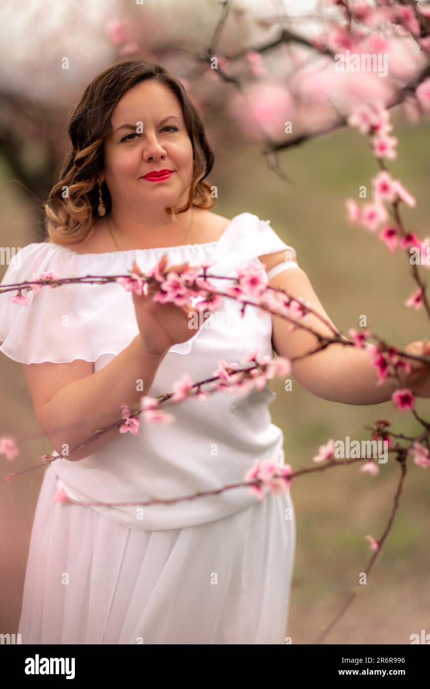 Woman peach blossom. Happy woman in white dress walking in the garden ...