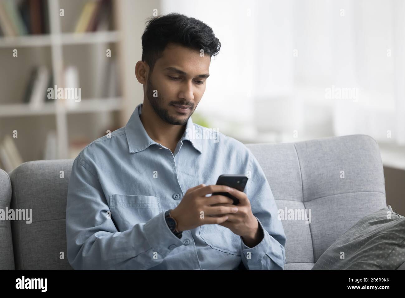 Serious handsome young Indian man using gadget for Internet ...