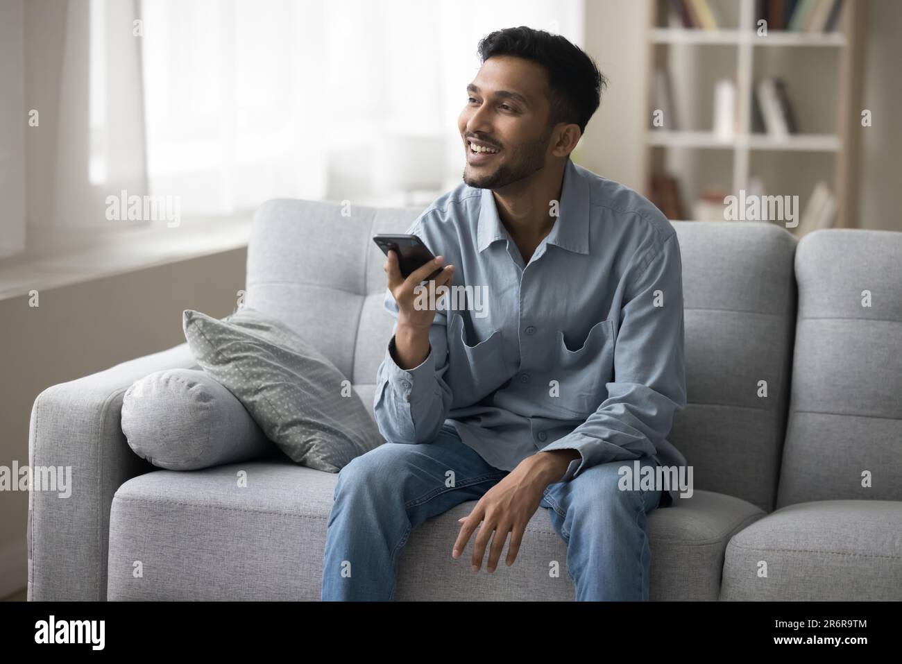Cheerful attractive young Indian man speaking voice message Stock Photo ...