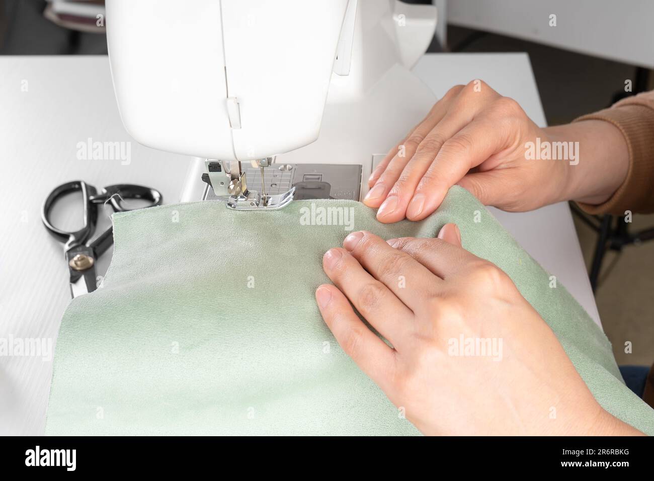 Female hands stitching white fabric on modern sewing machine at ...
