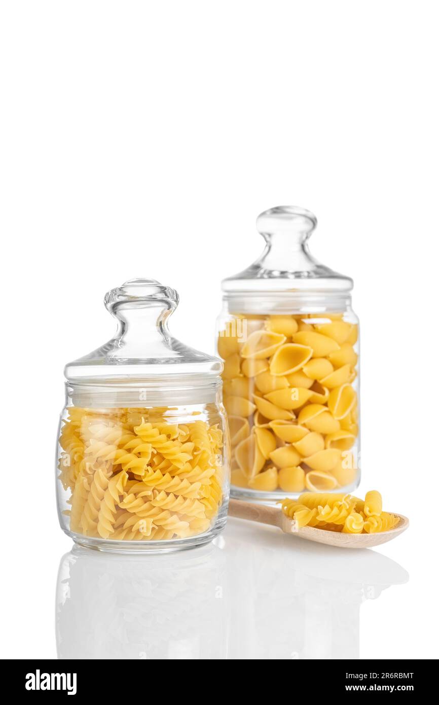 Fusilli and conchiglioni in glass jar isolated on white background. Two ...