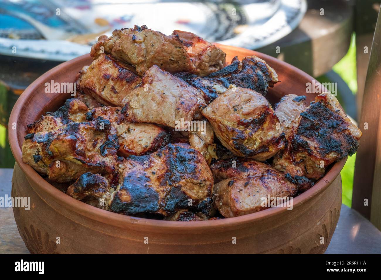 Clay bowl full of freshly cooked juicy grilled meat. Summer barbeque ...