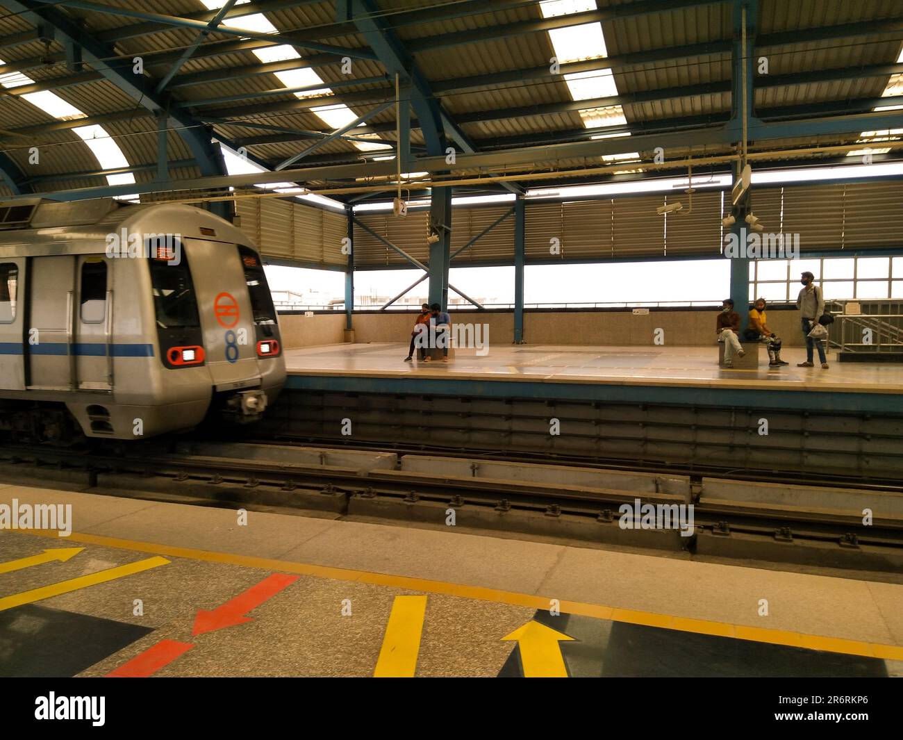 A group of people boarding a gleaming silver train at a station ...