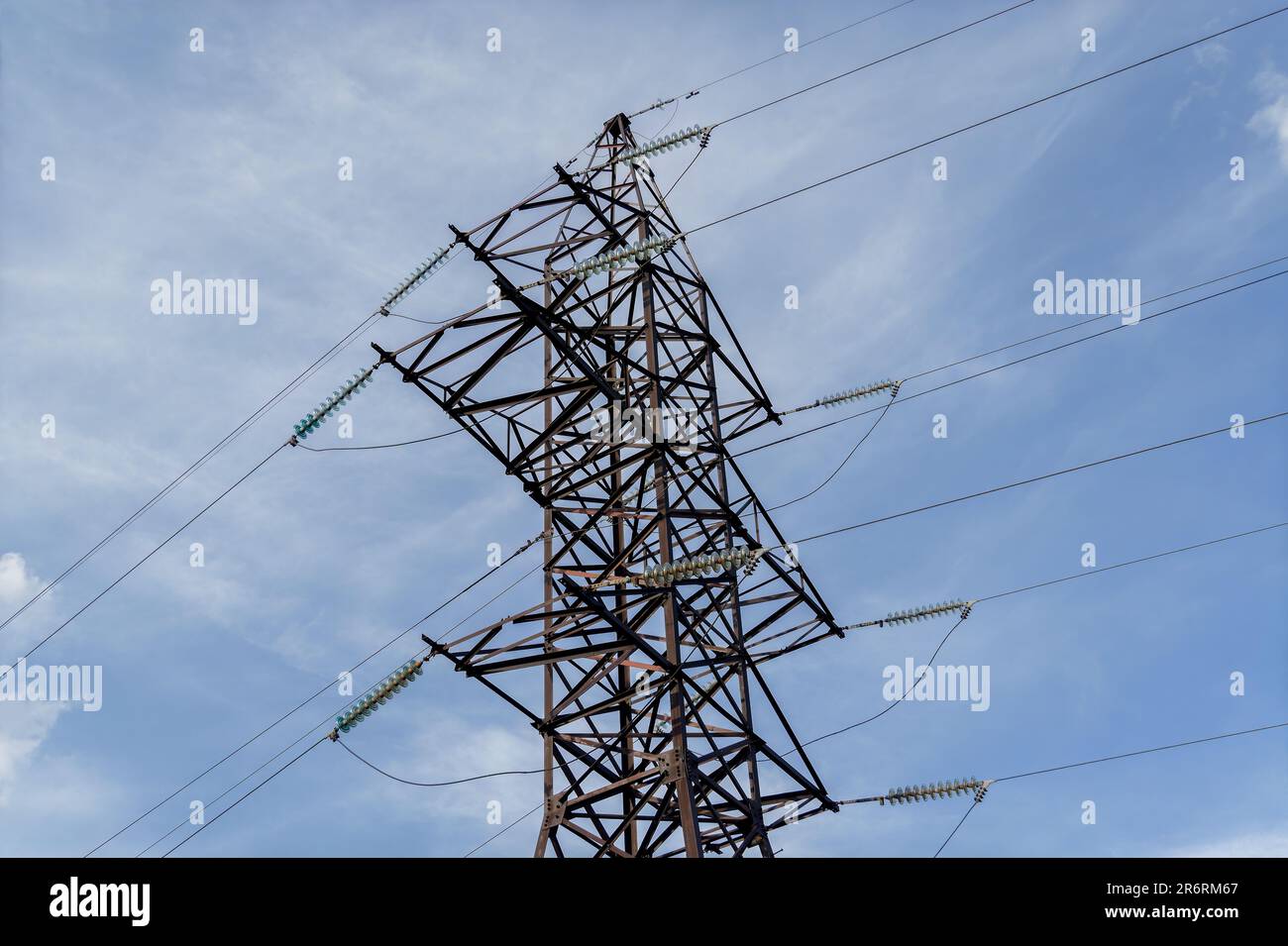 High voltage power lines pylons and electrical cables on a clear blue ...