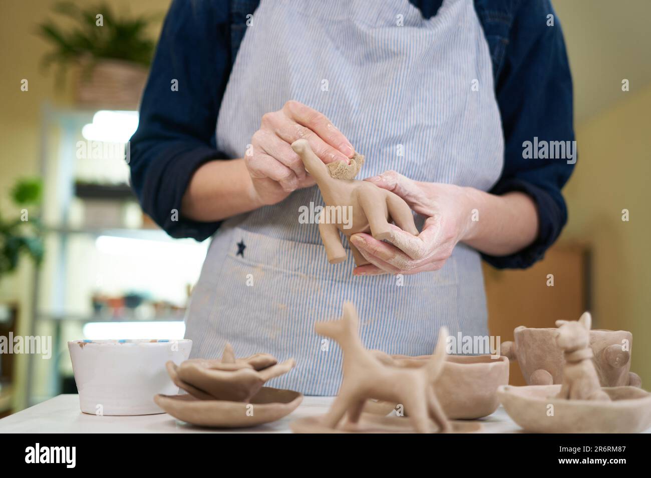 woman sculpts a figurine of a dsnosaur from clay by hands, closeup in ...