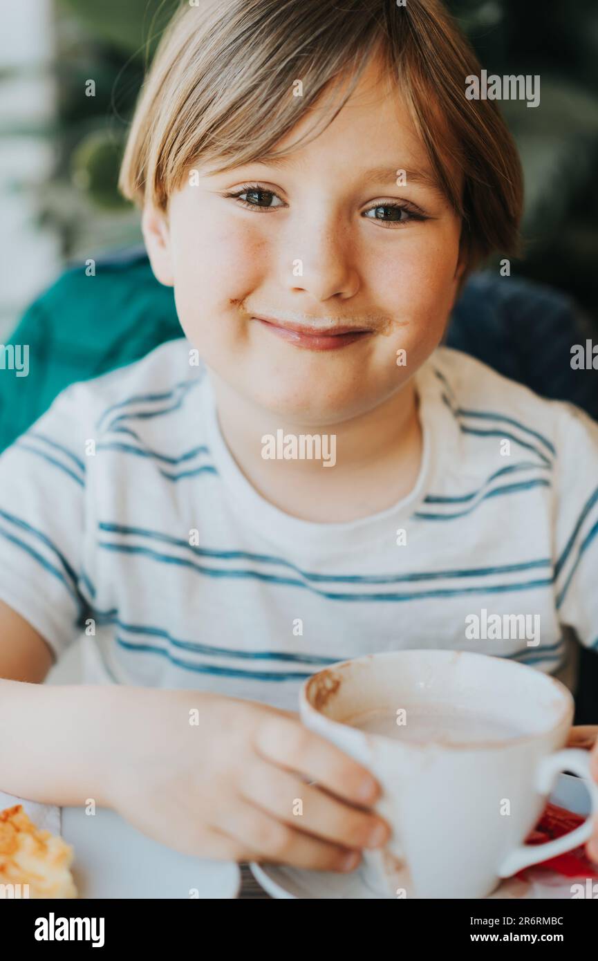 Funny little boy drinking hot chocolate for breakfast Stock Photo - Alamy