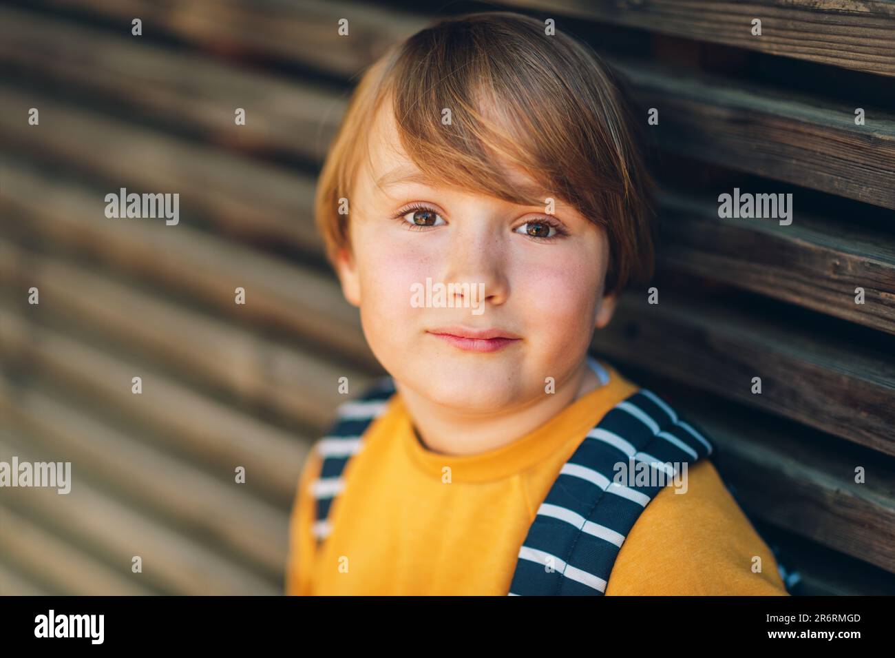 Outdoor portrait of cute kid boy wearing yellow sweatshirt and backpack ...