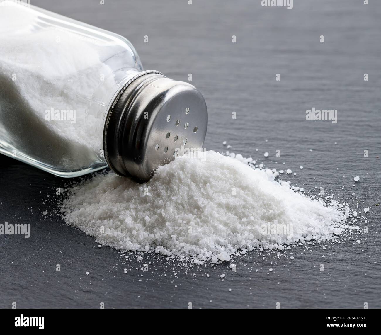Salt glass jar and pile of spilled salt on a slate stone plate Stock ...