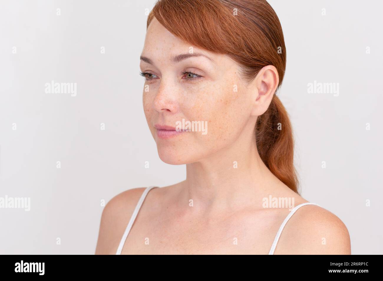 Portrait of cropped caucasian middle aged woman face with freckles touching skin by hand on ...