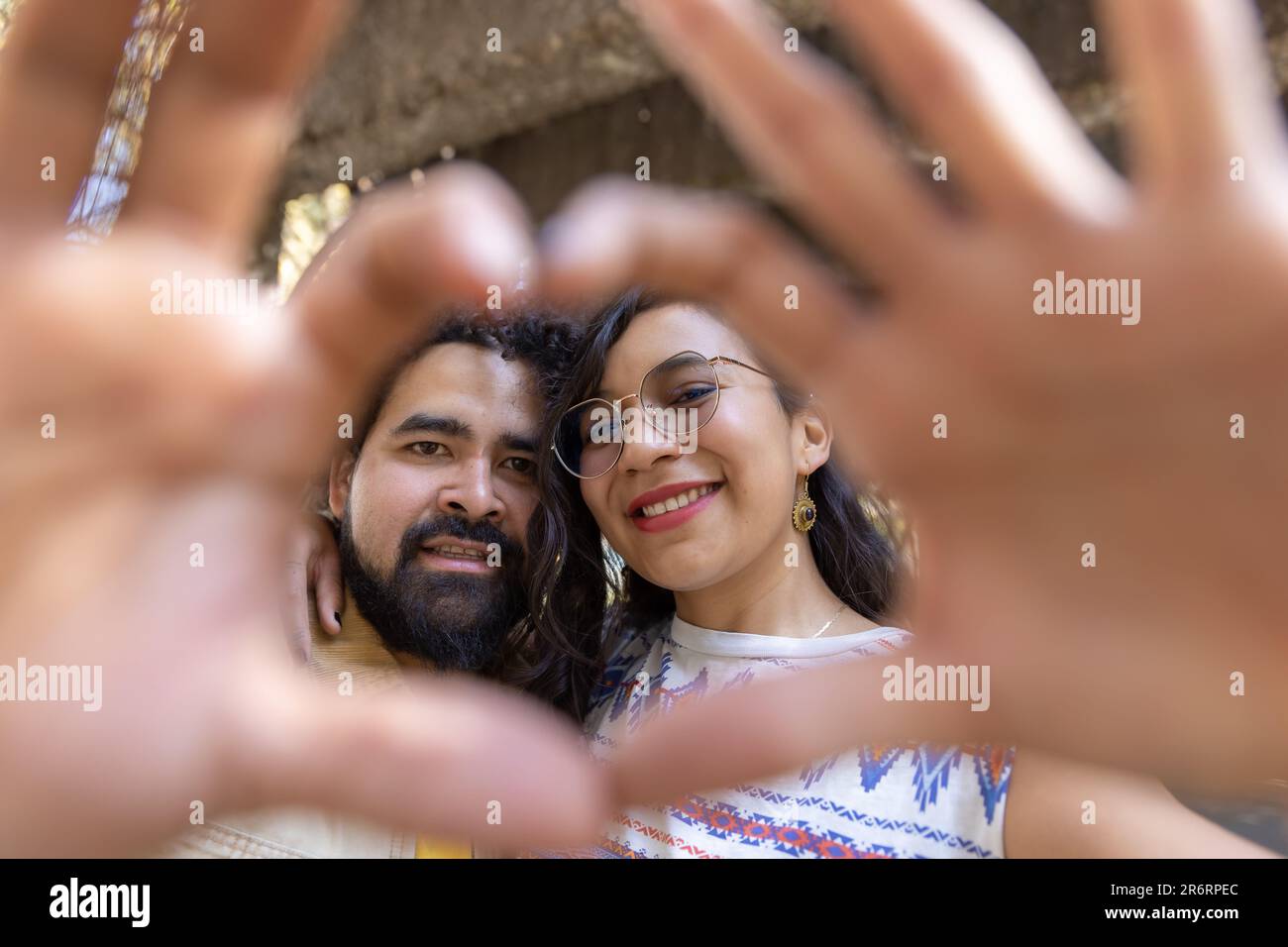Two people posing together while making a heart shape with their hands ...