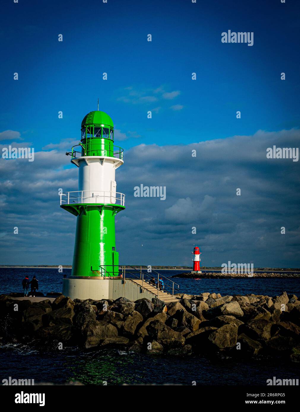 An aerial view of green lighthouse surrounded by rocky shores along a ...