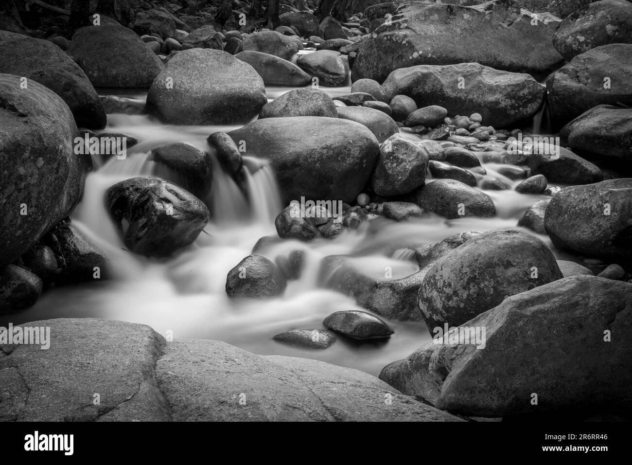 River with rounded rocks photographed with long exposure in black and ...