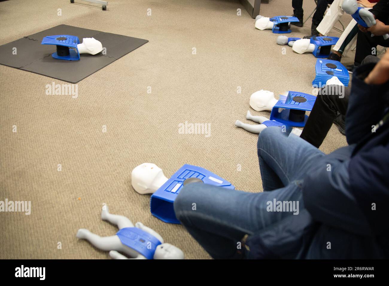A classroom of students learning the basics of first aid with a doll ...