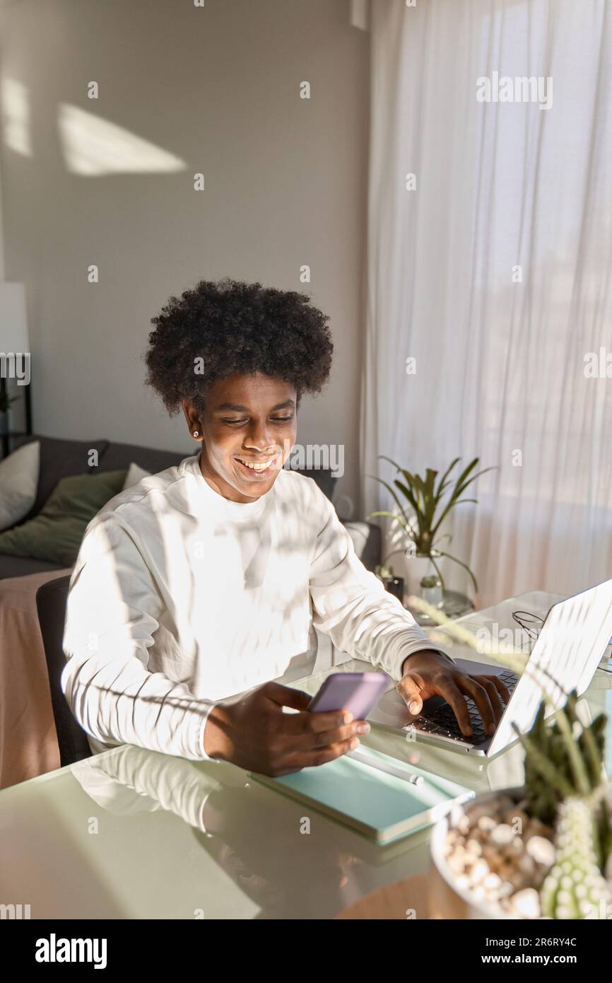 African American gen z teen student using mobile phone and laptop at ...