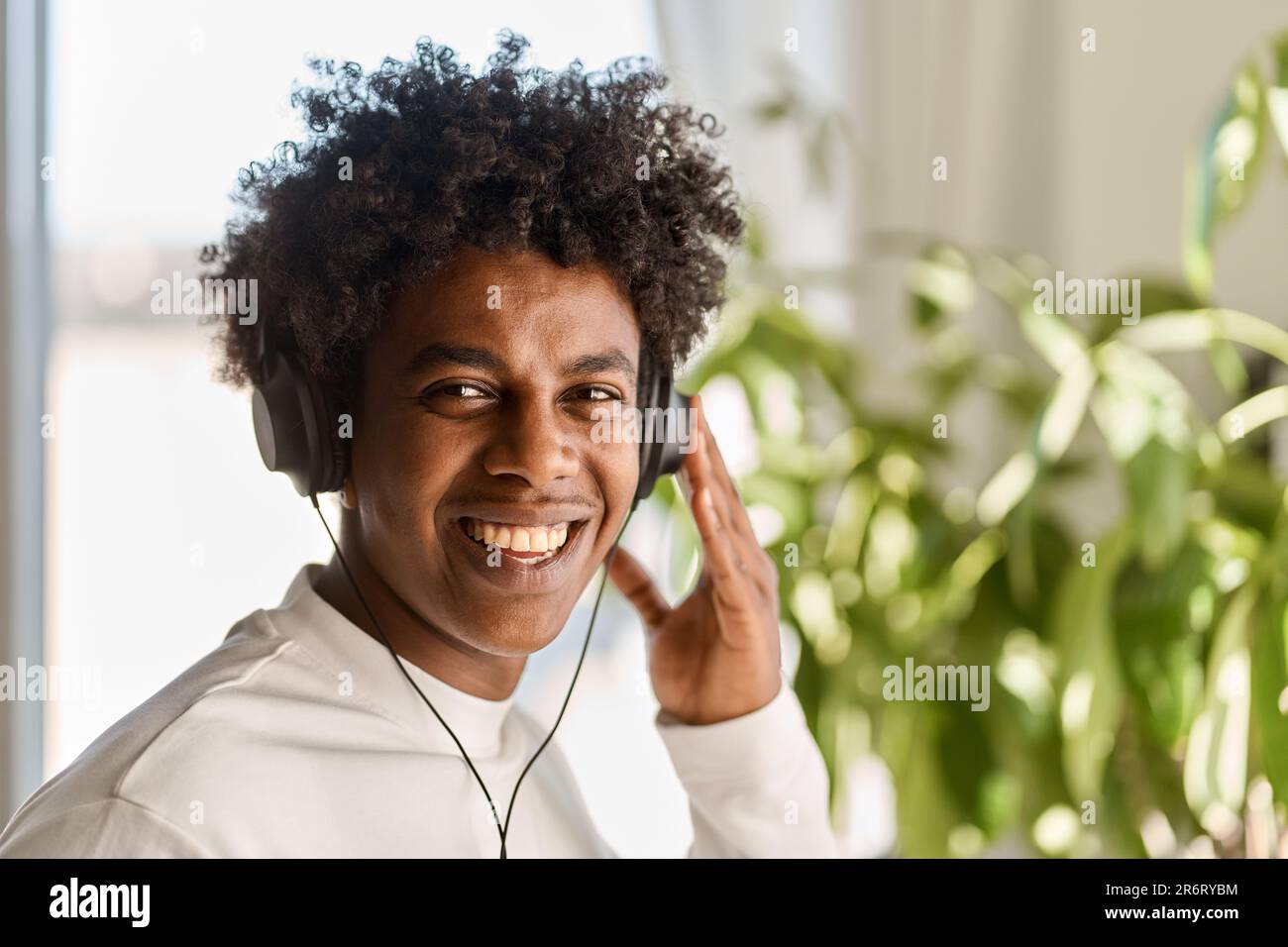 Happy gen z African American guy wearing headphones listening music at ...