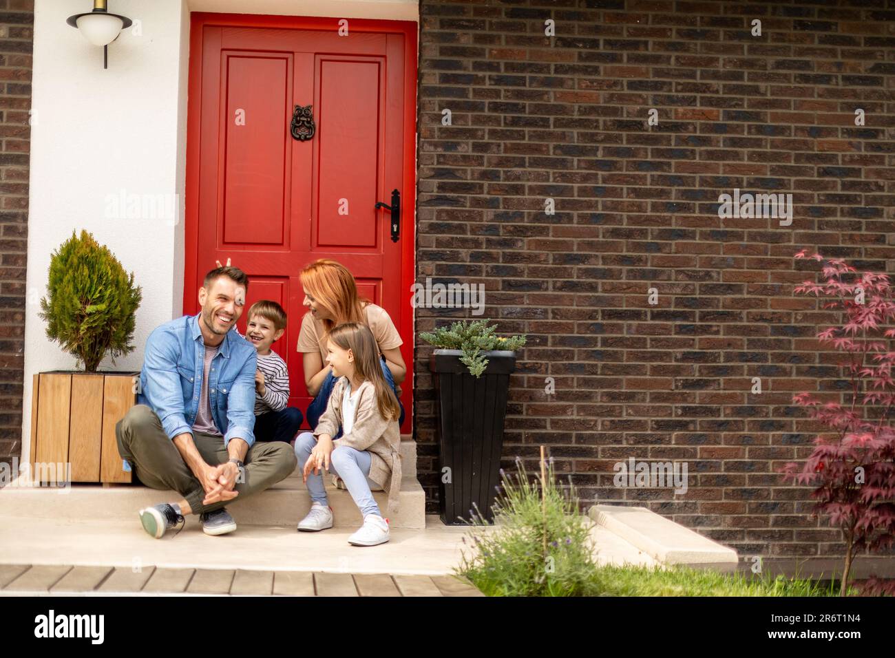 Family with a mother, father, son and daughter sitting outside on steps ...