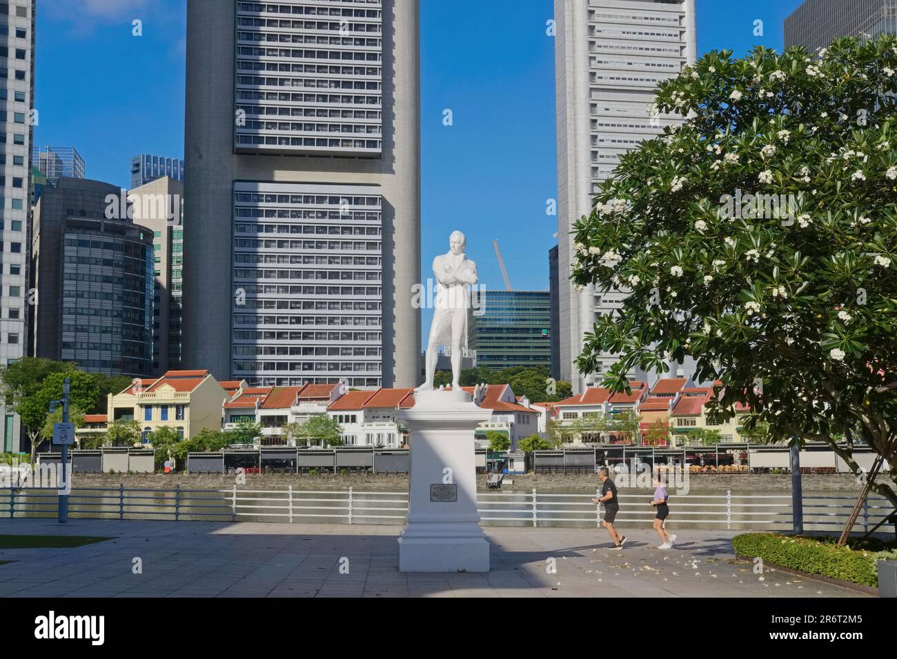 A couple jogs past a statue of Sir Stamford Raffles at Raffles' Landing Site by the Singapore ...