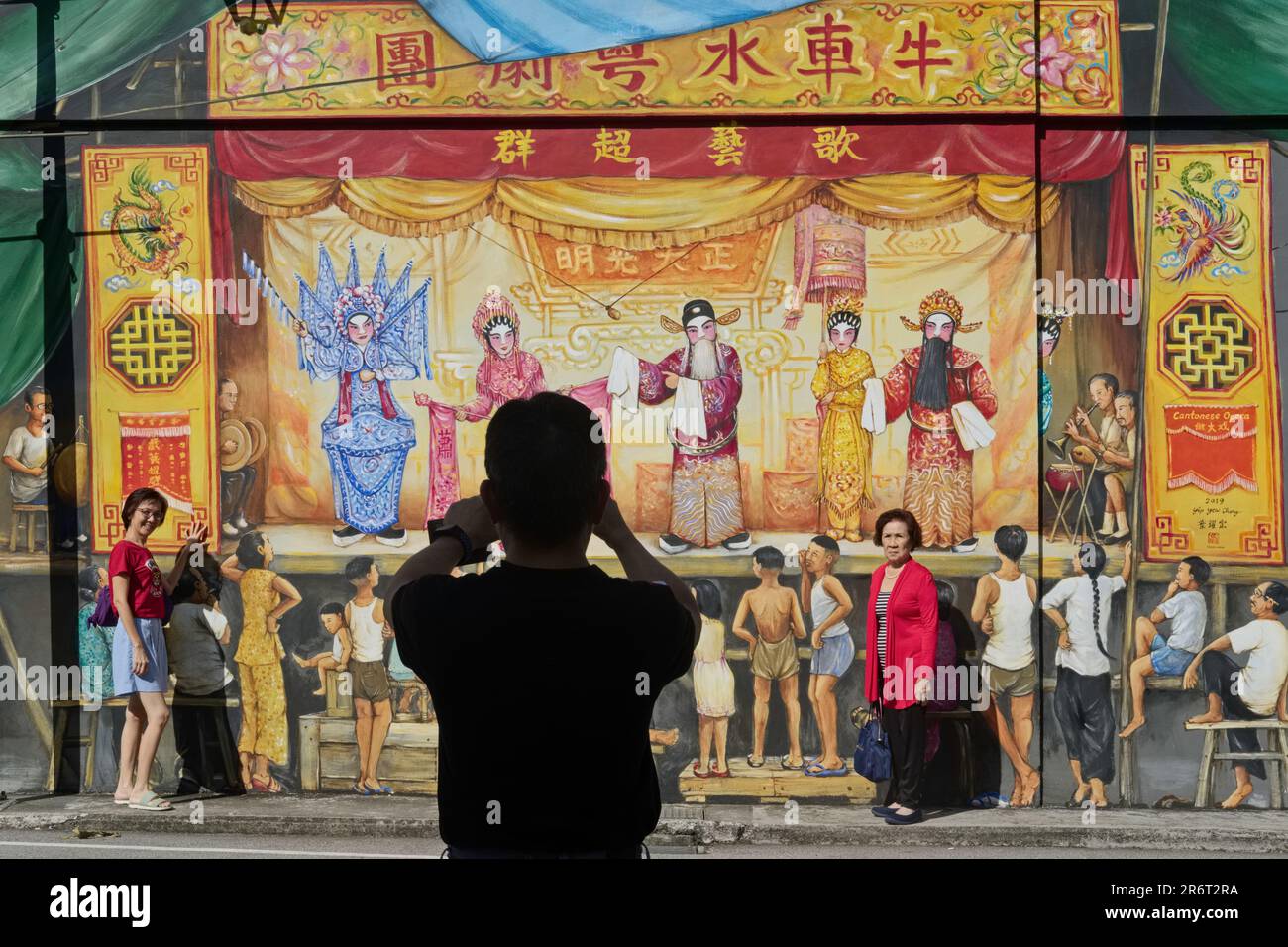 A male Asian tourist takes photos of his family in front of a colorful ...