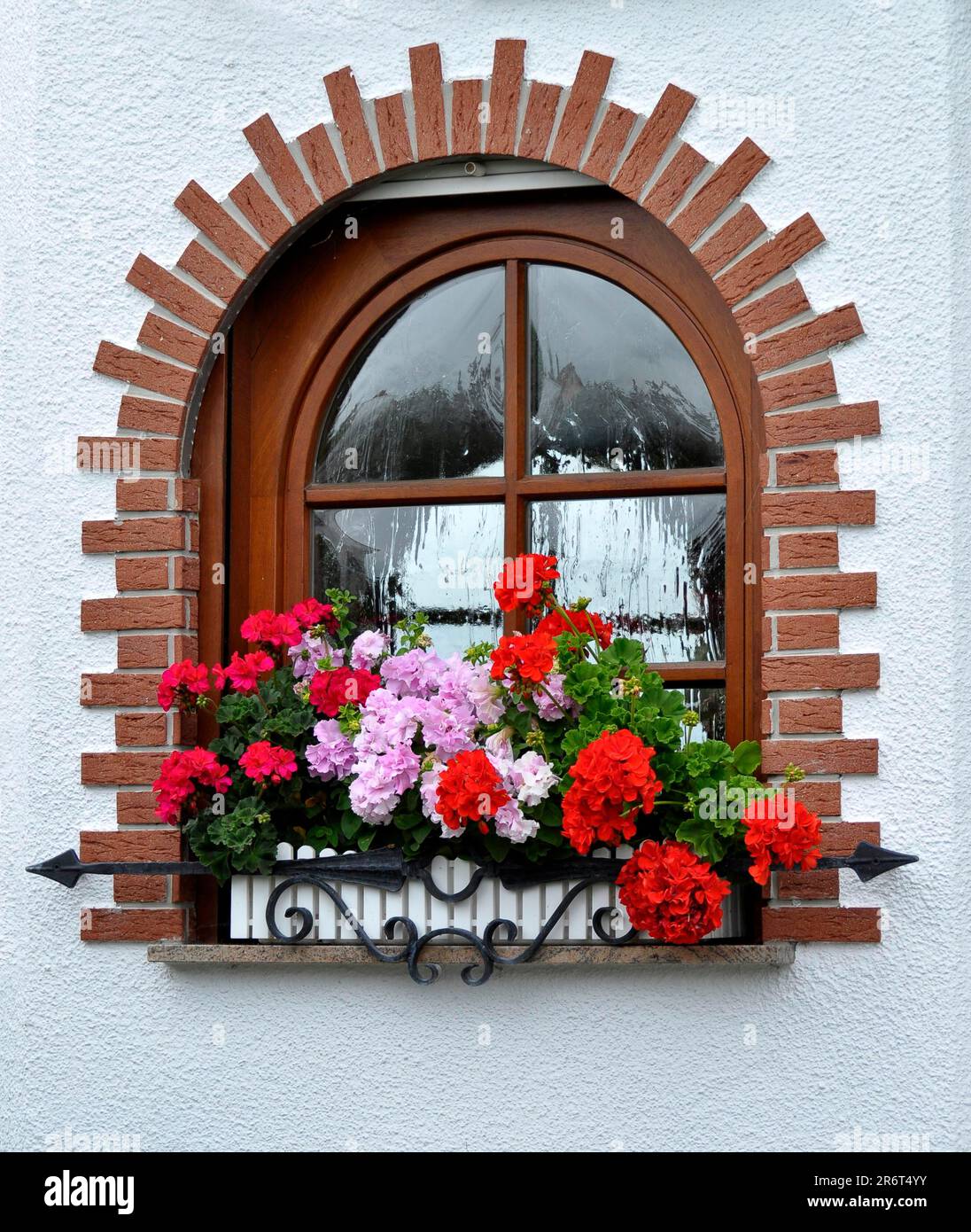 Garden with house, arched window with flowers, geraniums at the window ...