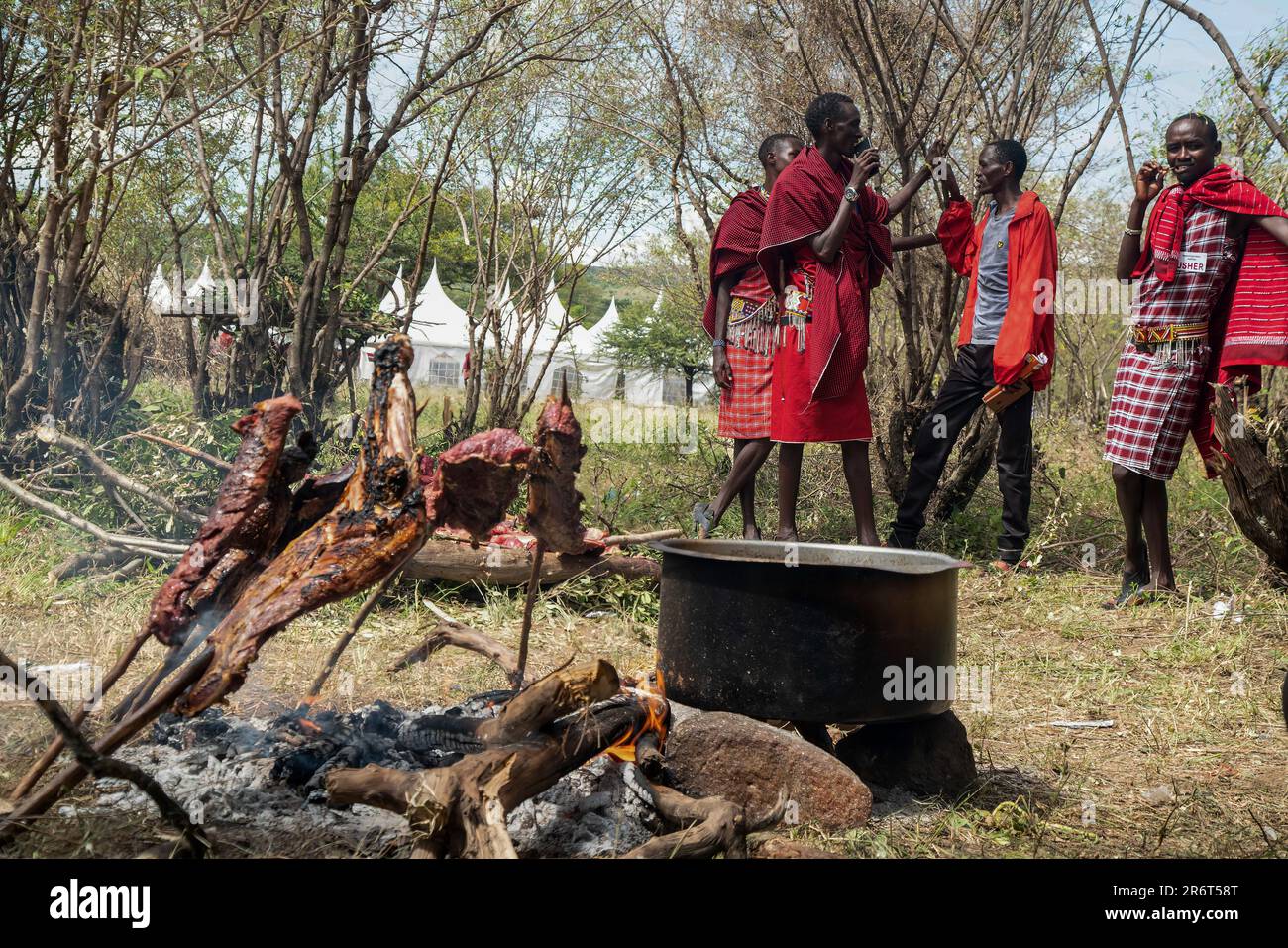 Narok, Kenya. 10th June, 2023. Maasai men dressed in their traditional shukas watch as meat ...