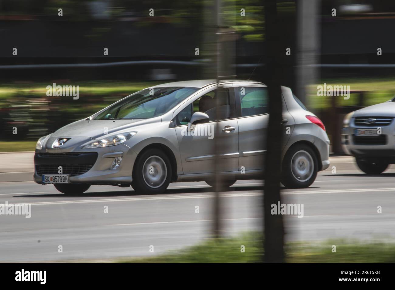Grey car / peugeot driving fast / speeding down a busy boulevard ...