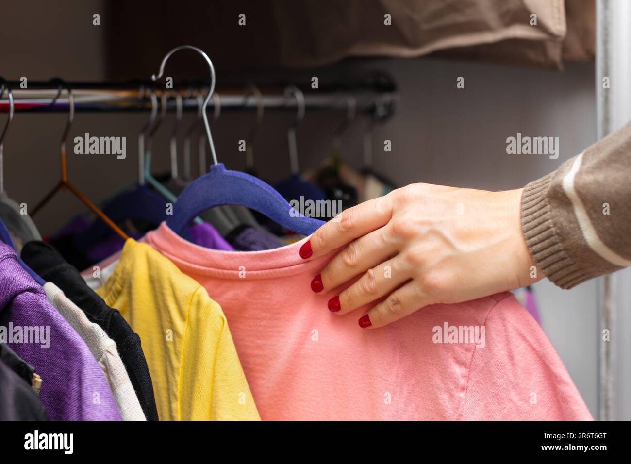 a woman takes a t-shirt out of the closet with clothes. hand holding ...