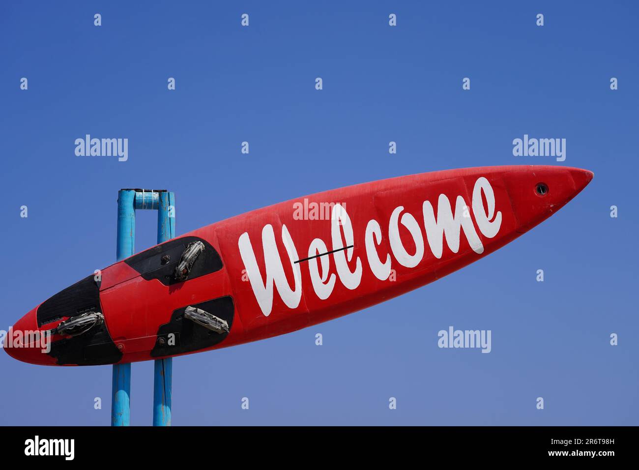 Welcome sign on surfboard hanging in the air against a blue sky Stock ...