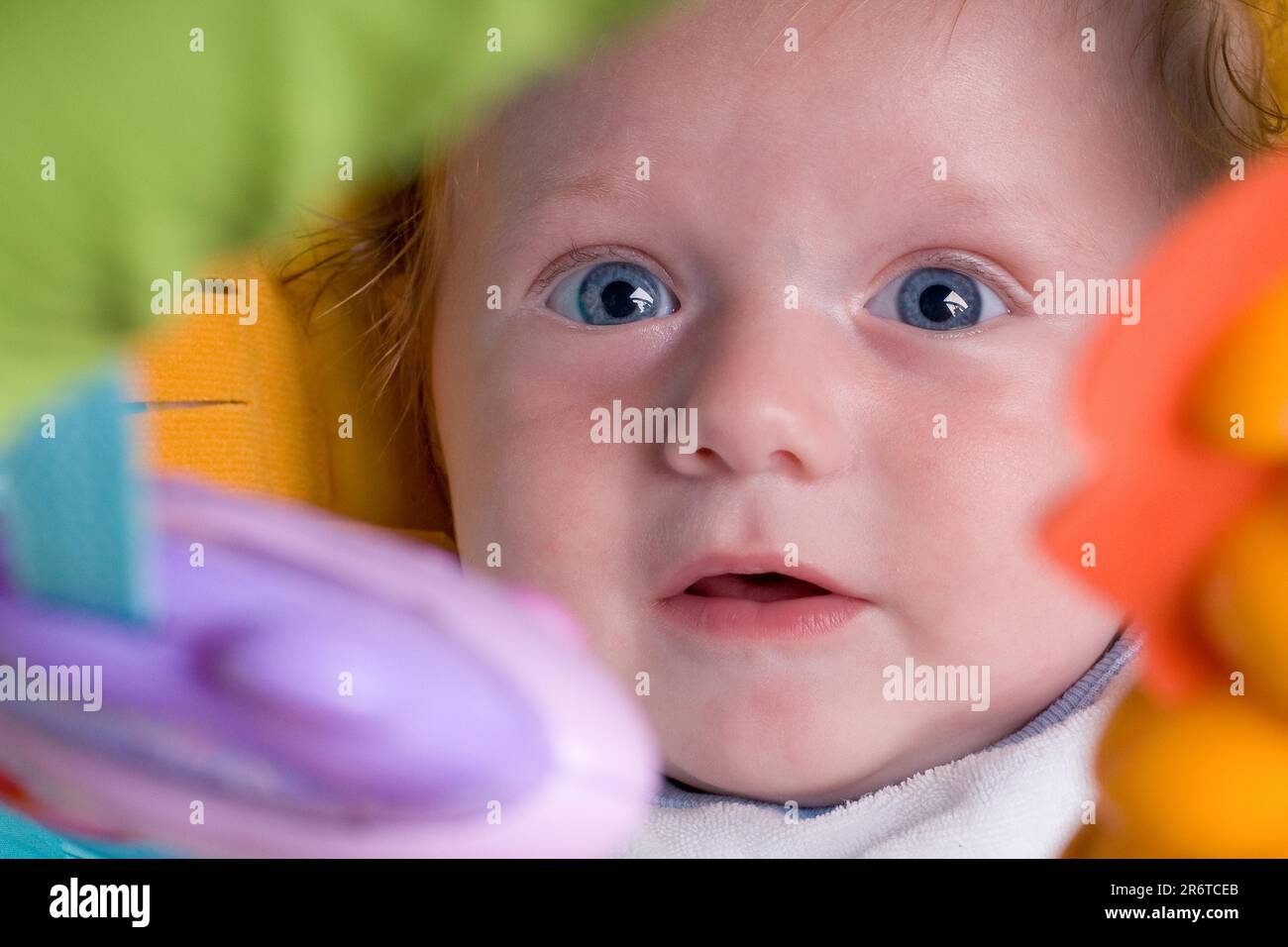 Baby with coloured background looks scared Stock Photo - Alamy