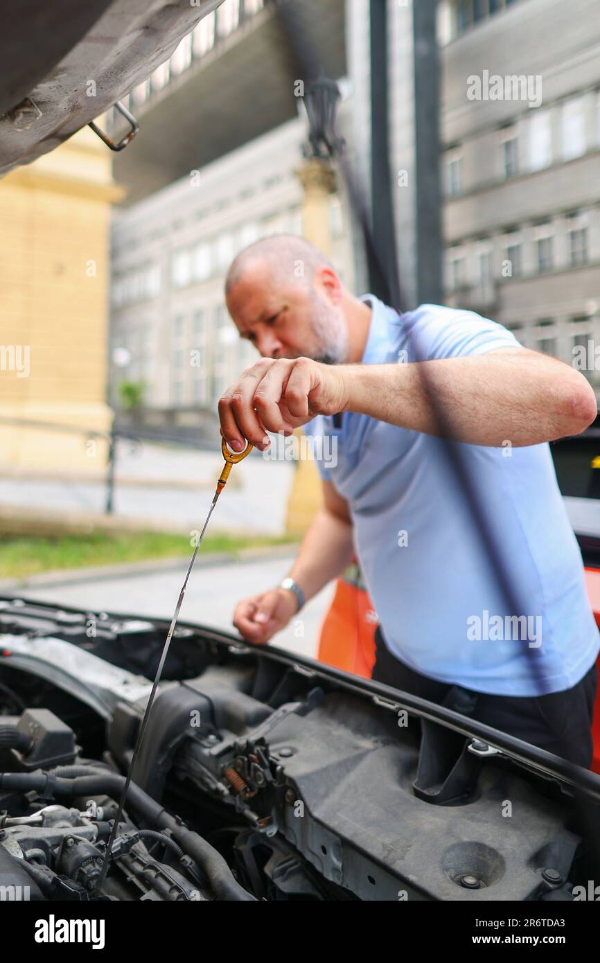 Senior mechanic checking the oil level in the car engine Stock Photo - Alamy