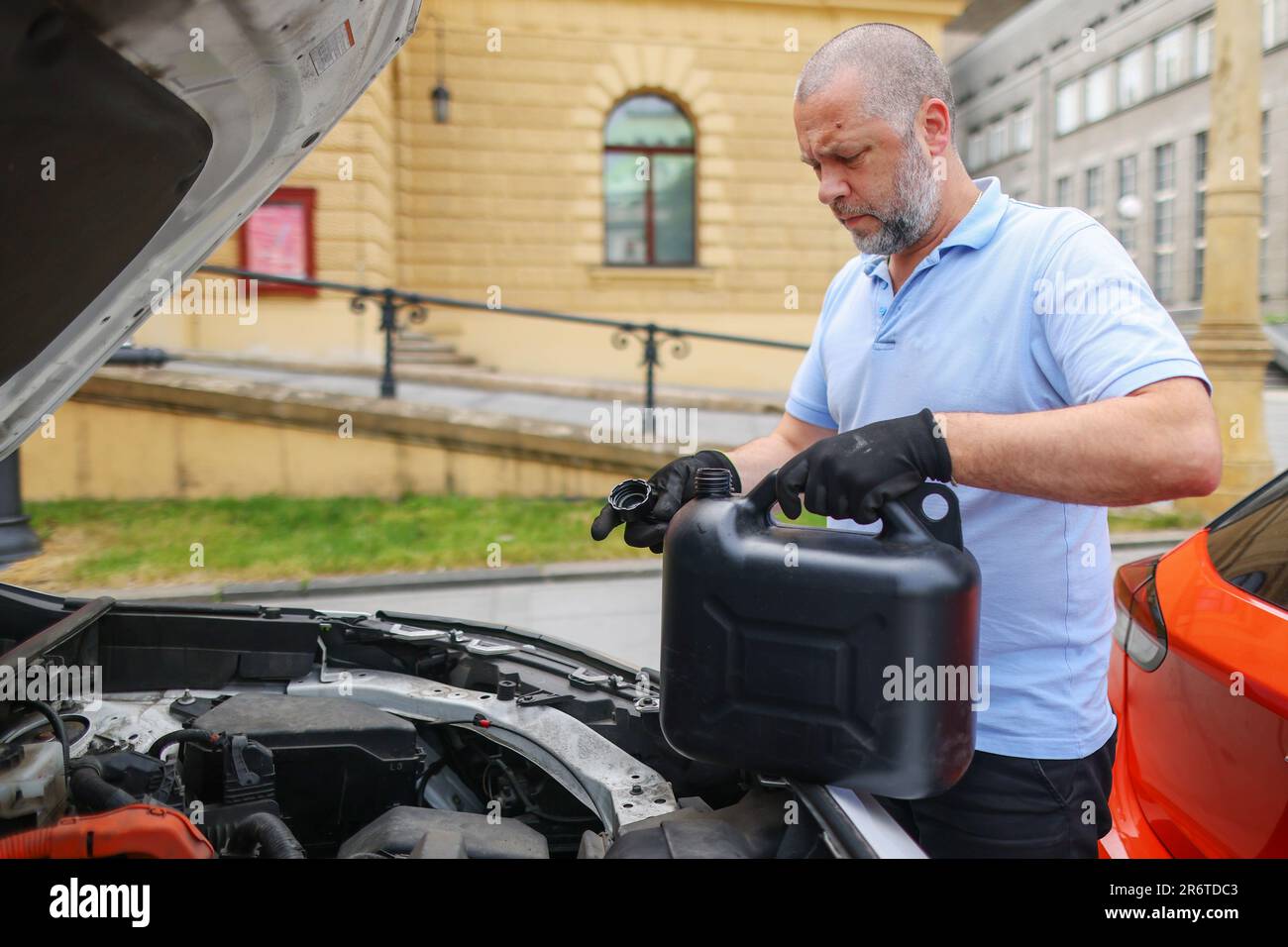 The mechanic is pouring oil into the engine. Pouring fresh oil to car ...