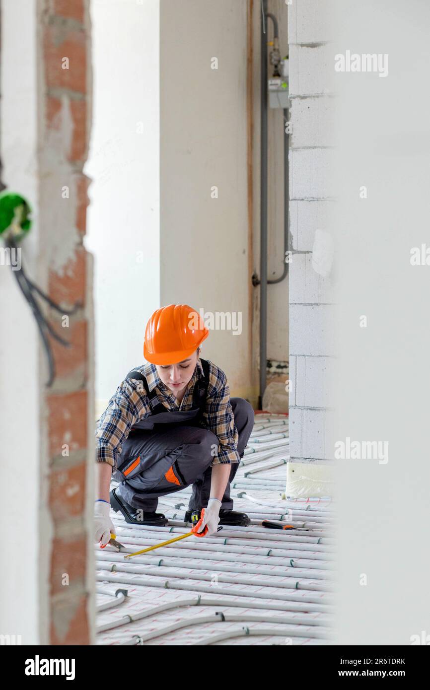 A female construction worker checks the installation of a warm floor ...