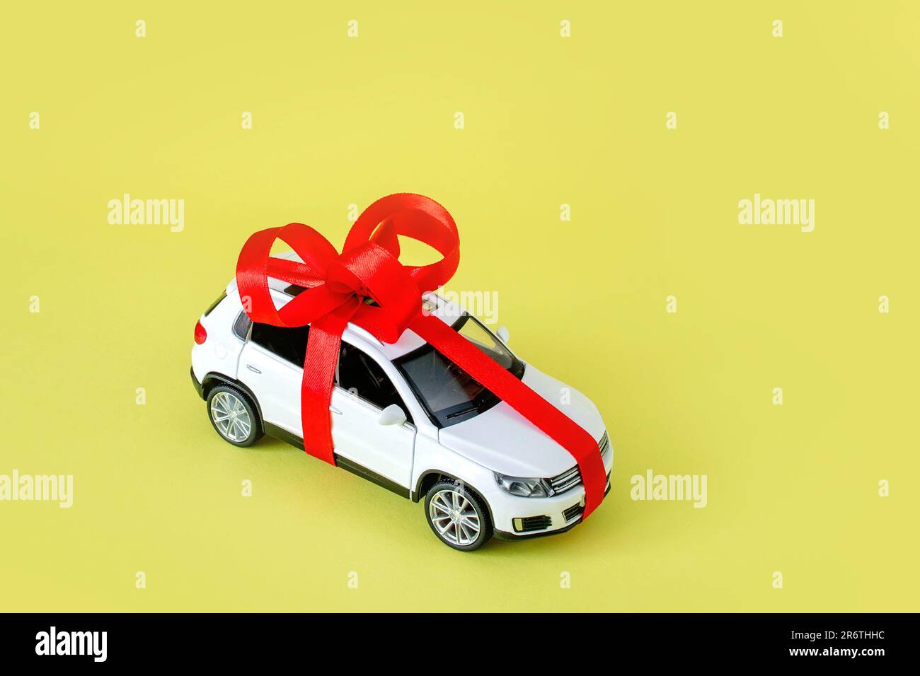 White model car with bow on a yellow background. Car as gift, surprise ...