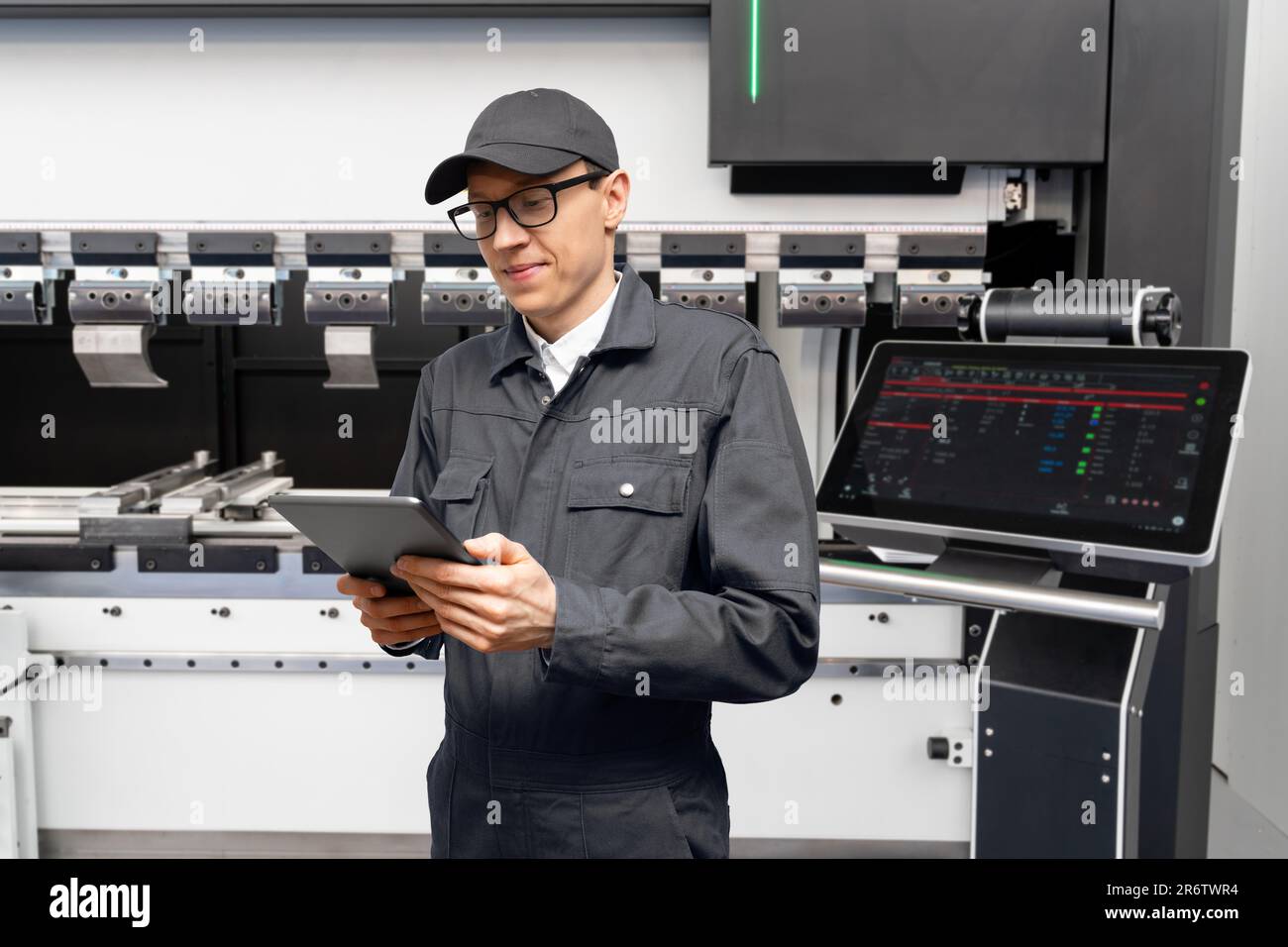 Worker with digital tablet controls automatic machine tool in smart ...