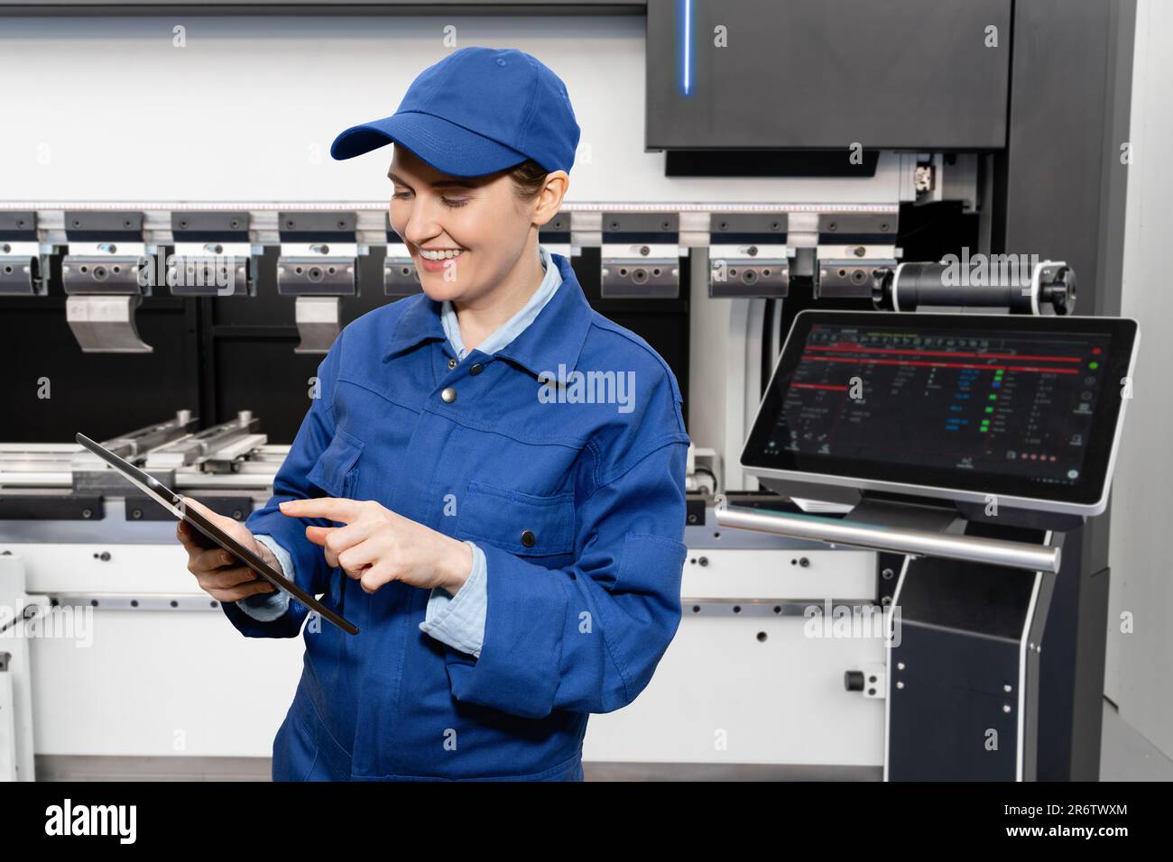 Worker with digital tablet controls automatic machine tool in smart ...