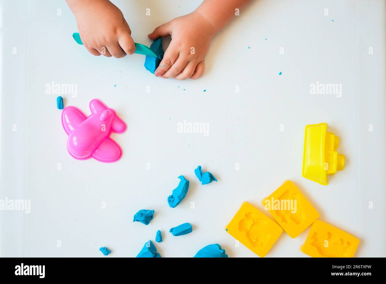 Little boy hands close up playing with blue modeling clay on white ...