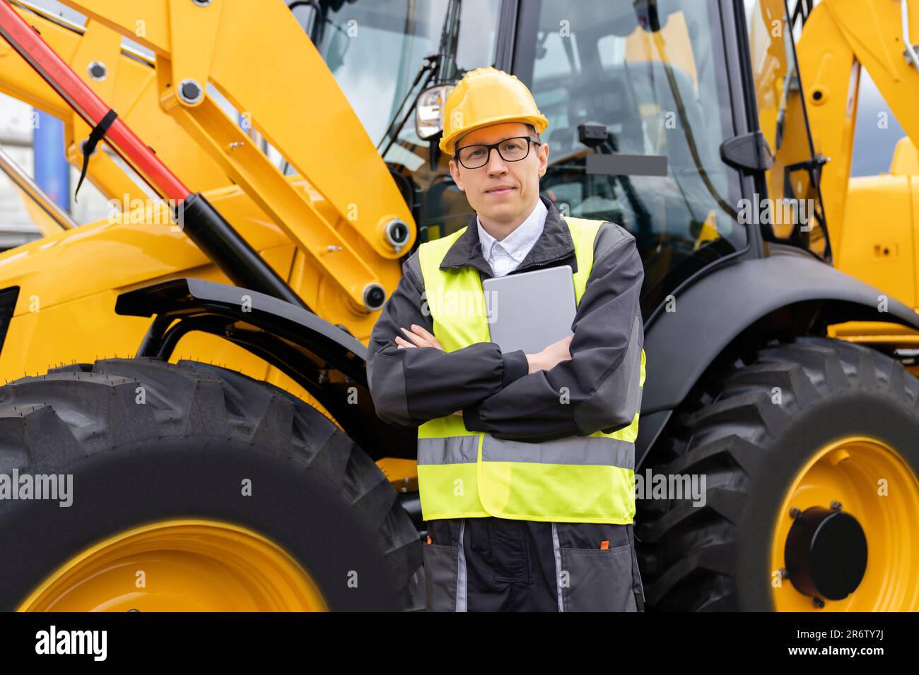 Engineer in a helmet with a digital tablet stands next to construction ...