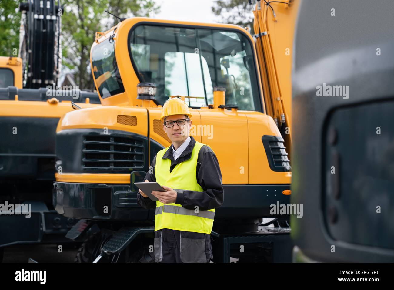 Engineer in a helmet with a digital tablet stands next to construction ...