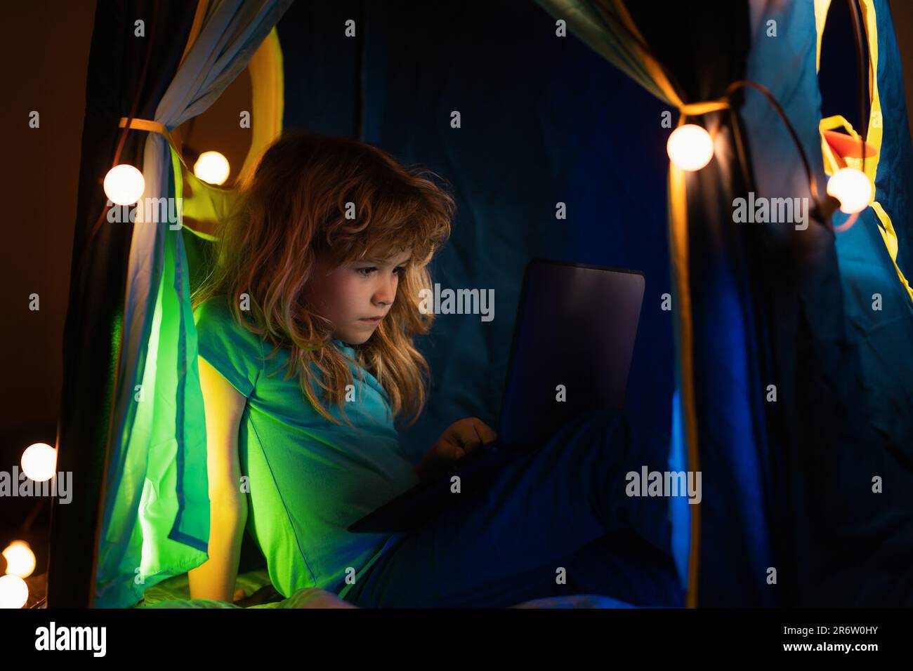Little kid using laptop by night, child boy illuminated by the blue ...