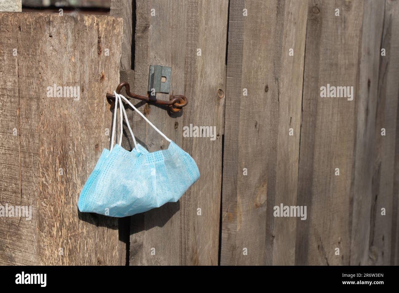 medical mask hanging on a hook an old wooden gate in Ukraine on the ...