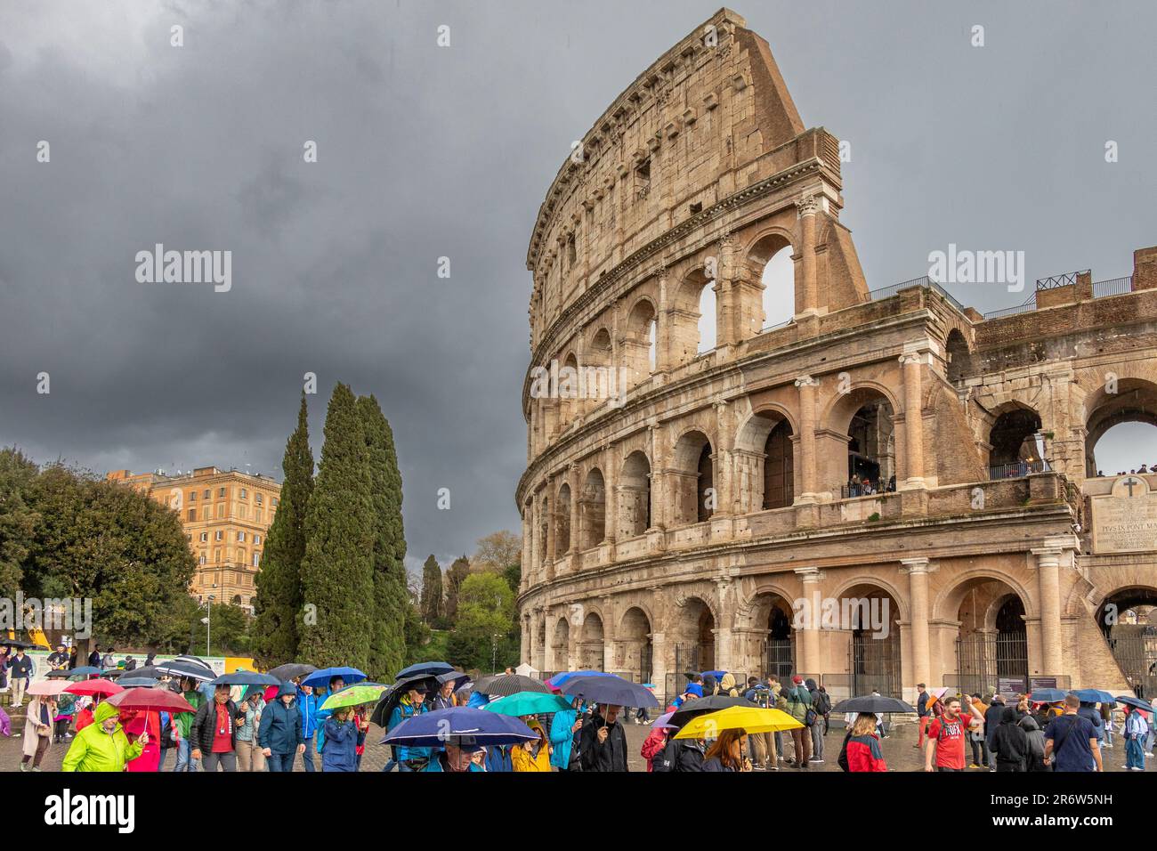 Visitors with umbrellas during heavy rain and dark stormy skies over ...