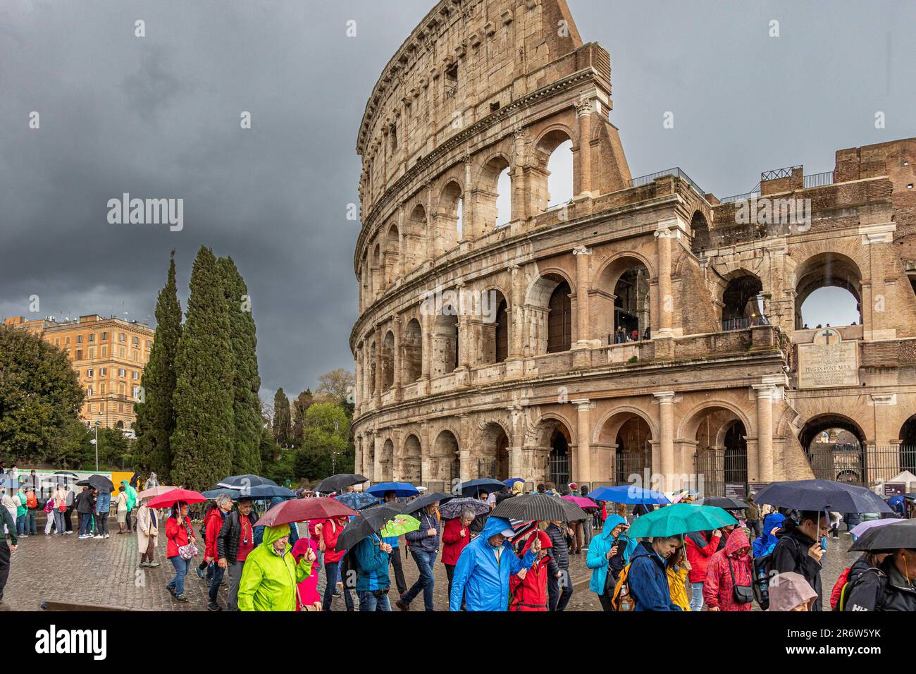 Visitors with umbrellas during heavy rain and dark stormy skies over ...