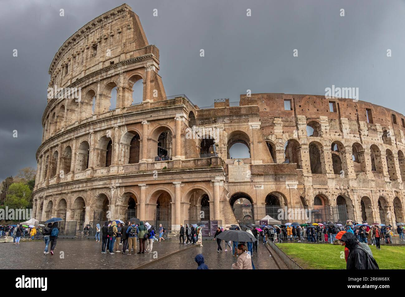 Visitors with umbrellas during heavy rain and dark stormy skies over ...