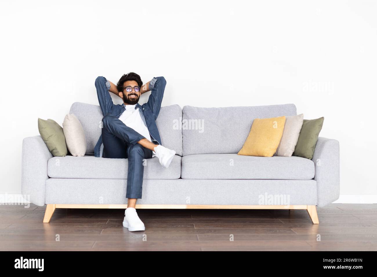Relaxed happy young eastern guy chilling on couch at home Stock Photo ...