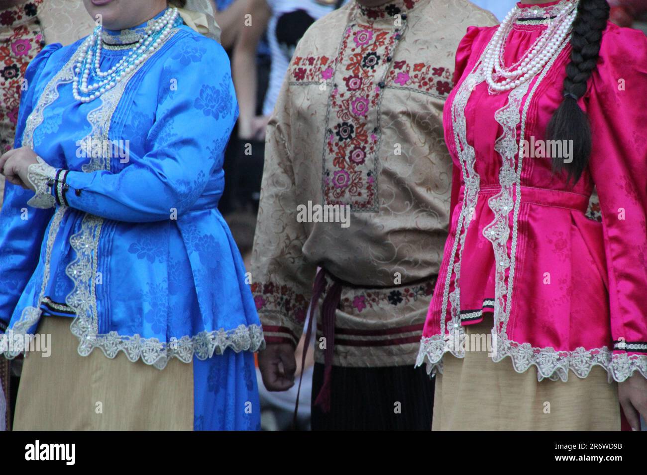 Three female models wearing colorful traditional costumes are walking ...