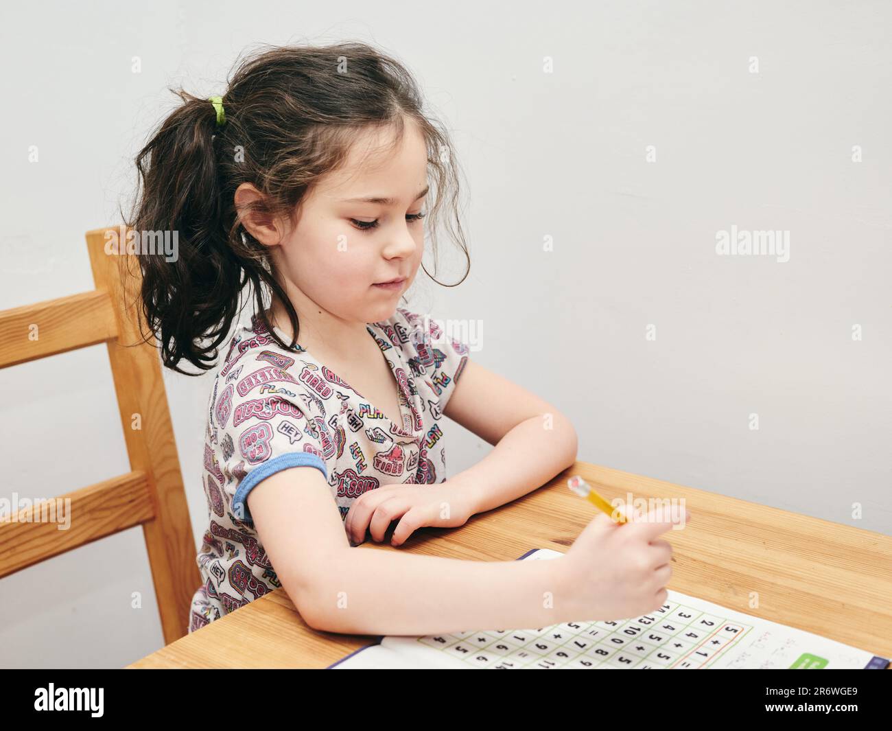 cute girl solving math puzzles at the kitchen table Stock Photo - Alamy